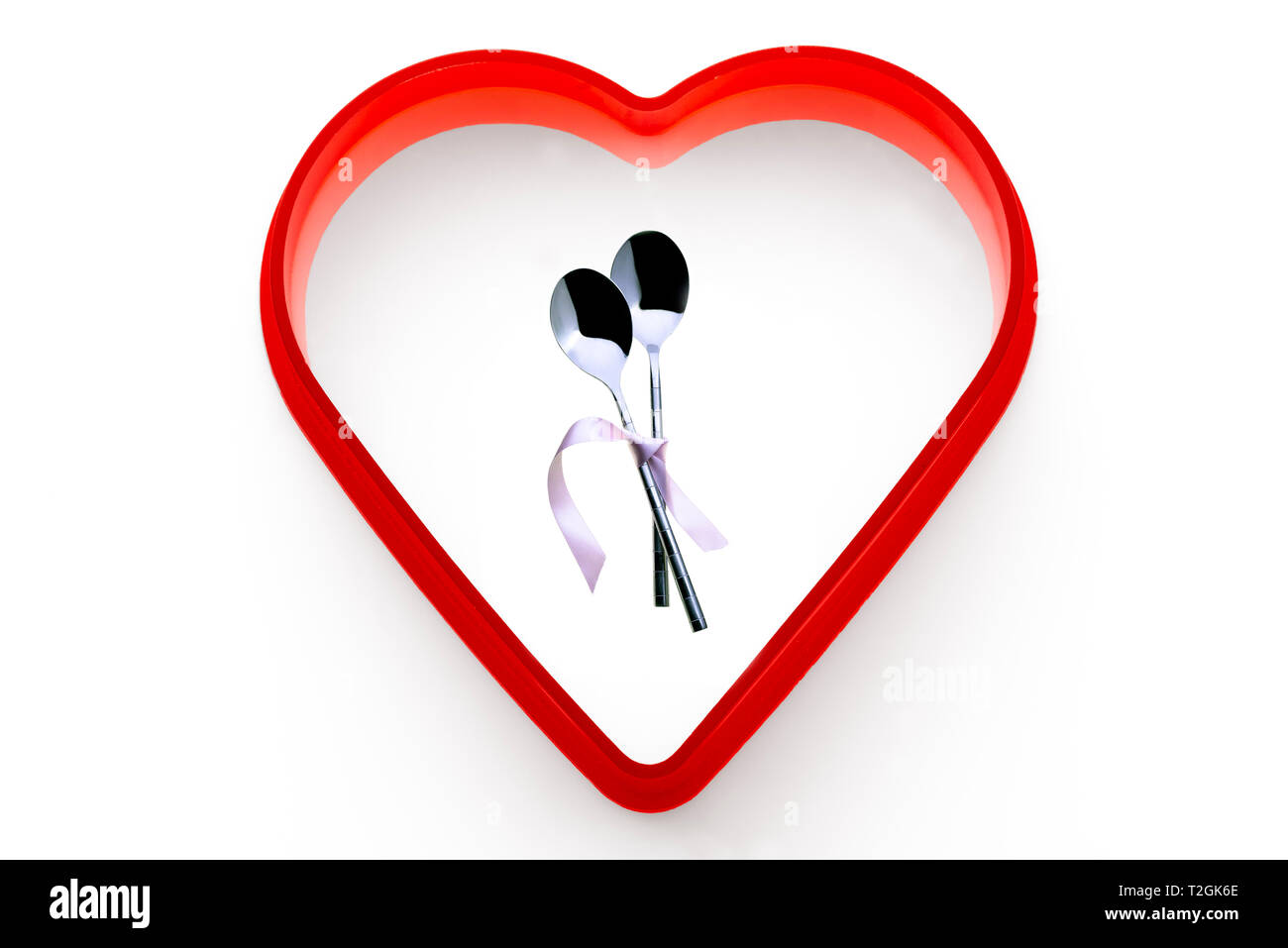 Two spoons tied together with pink ribbon.On a white background ...
