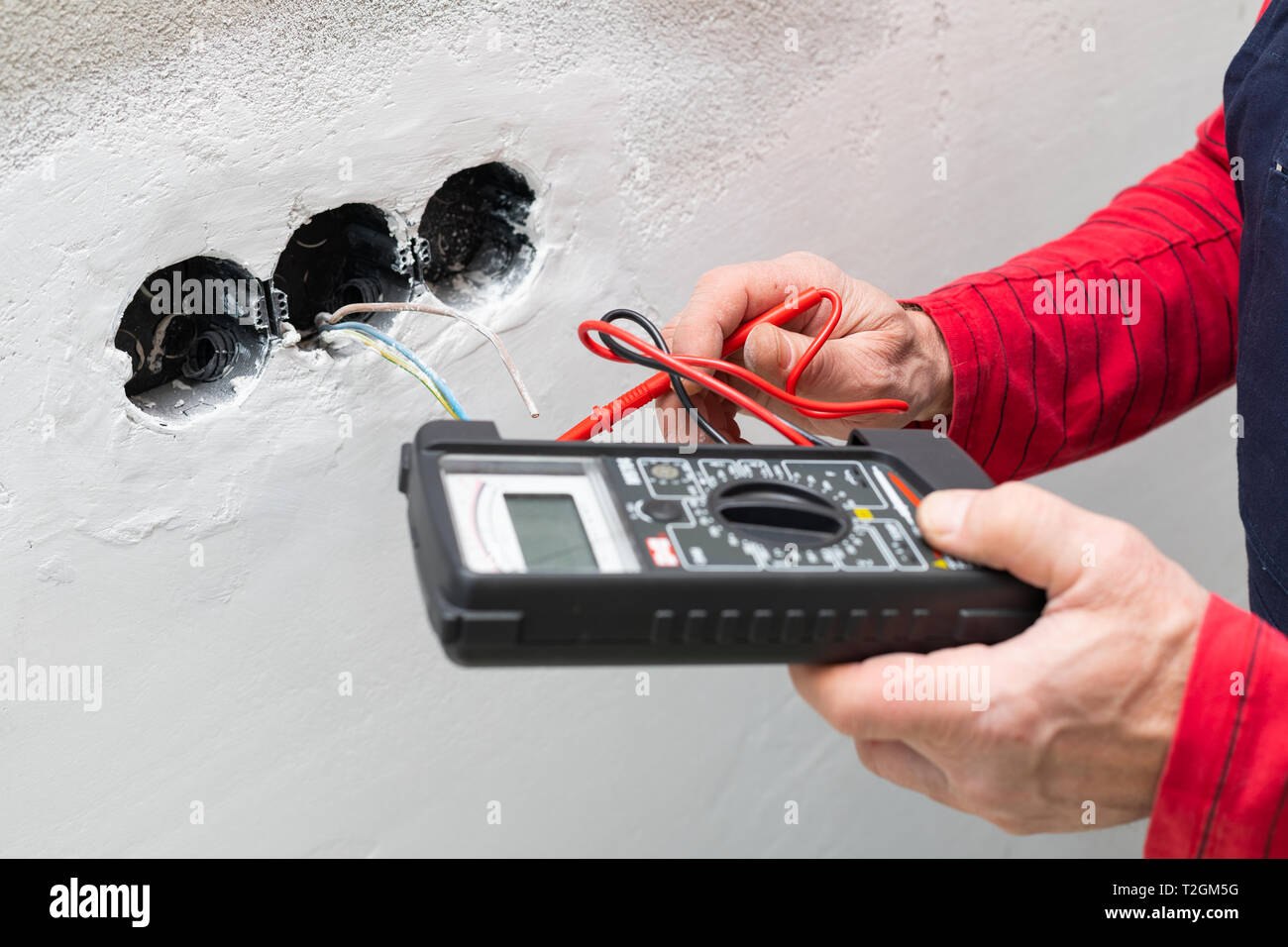 Electrician using voltmeter when installing electric sockets on the ...