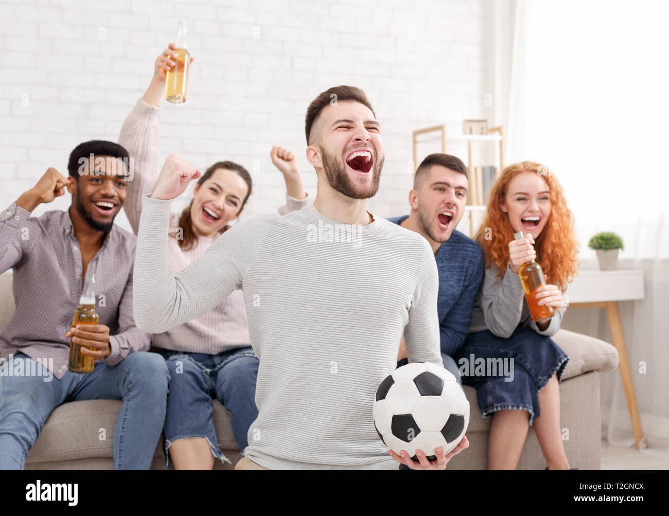 Happy football fans watching match on tv and celebrating victory at ...
