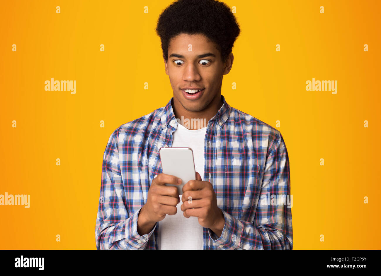 Shock content. Guy holding phone, chatting in social networks on yellow ...