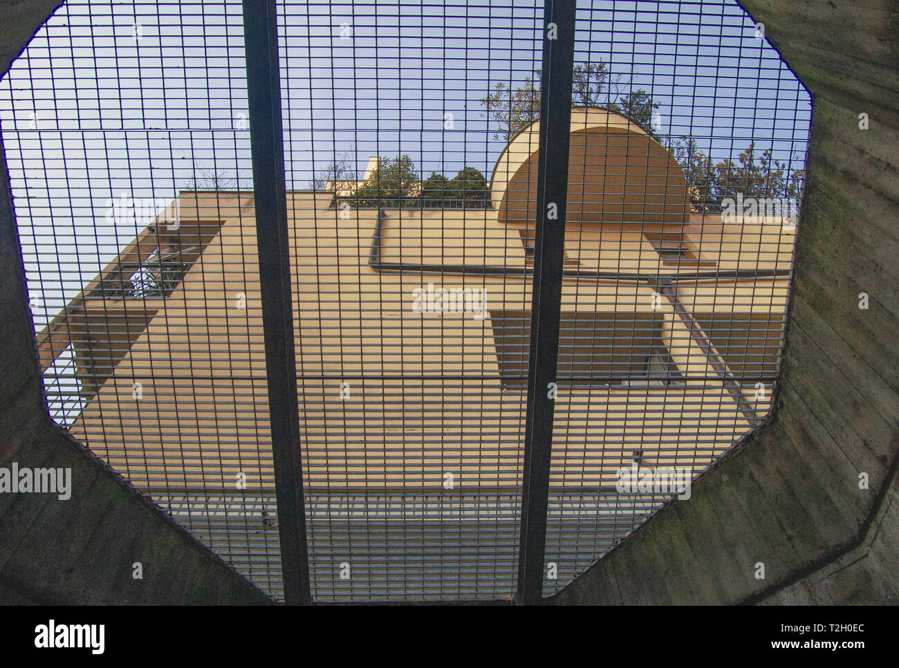 yellow facade of a building seen through a metal grate from the ...