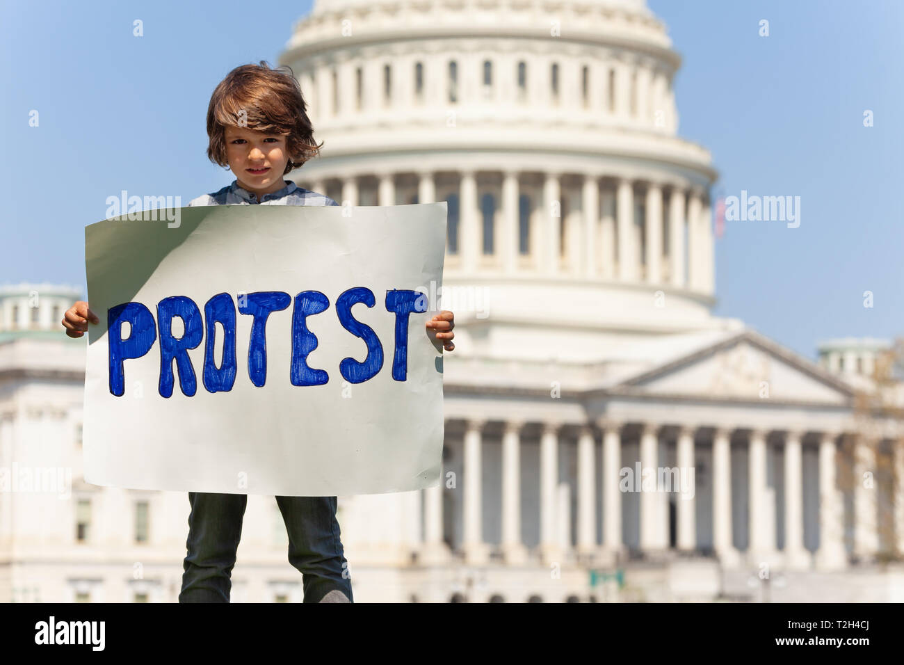 Child boy protesting in front of the USA capitol in Washington holding ...