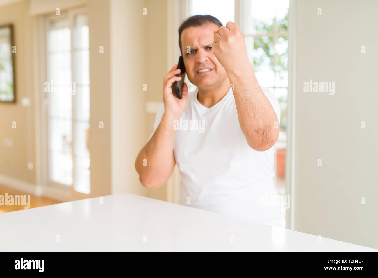 Middle age man calling using smartphone annoyed and frustrated shouting ...