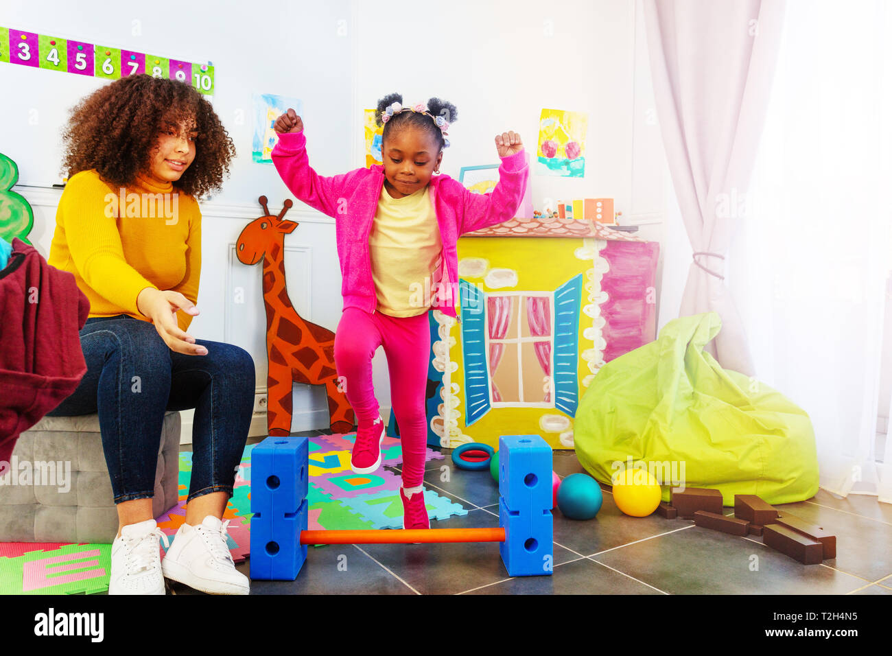 Developmental exercise in the kindergarten girl jumping over plank with ...