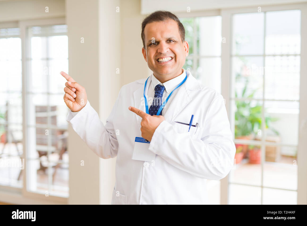 Middle age doctor man wearing medical coat and id card badge over white ...