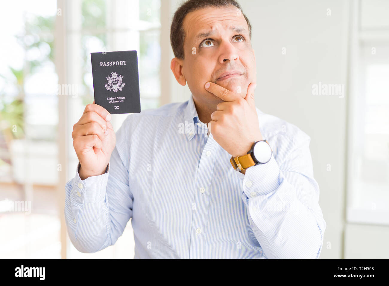 Middle age man holding holding passport of United States serious face ...
