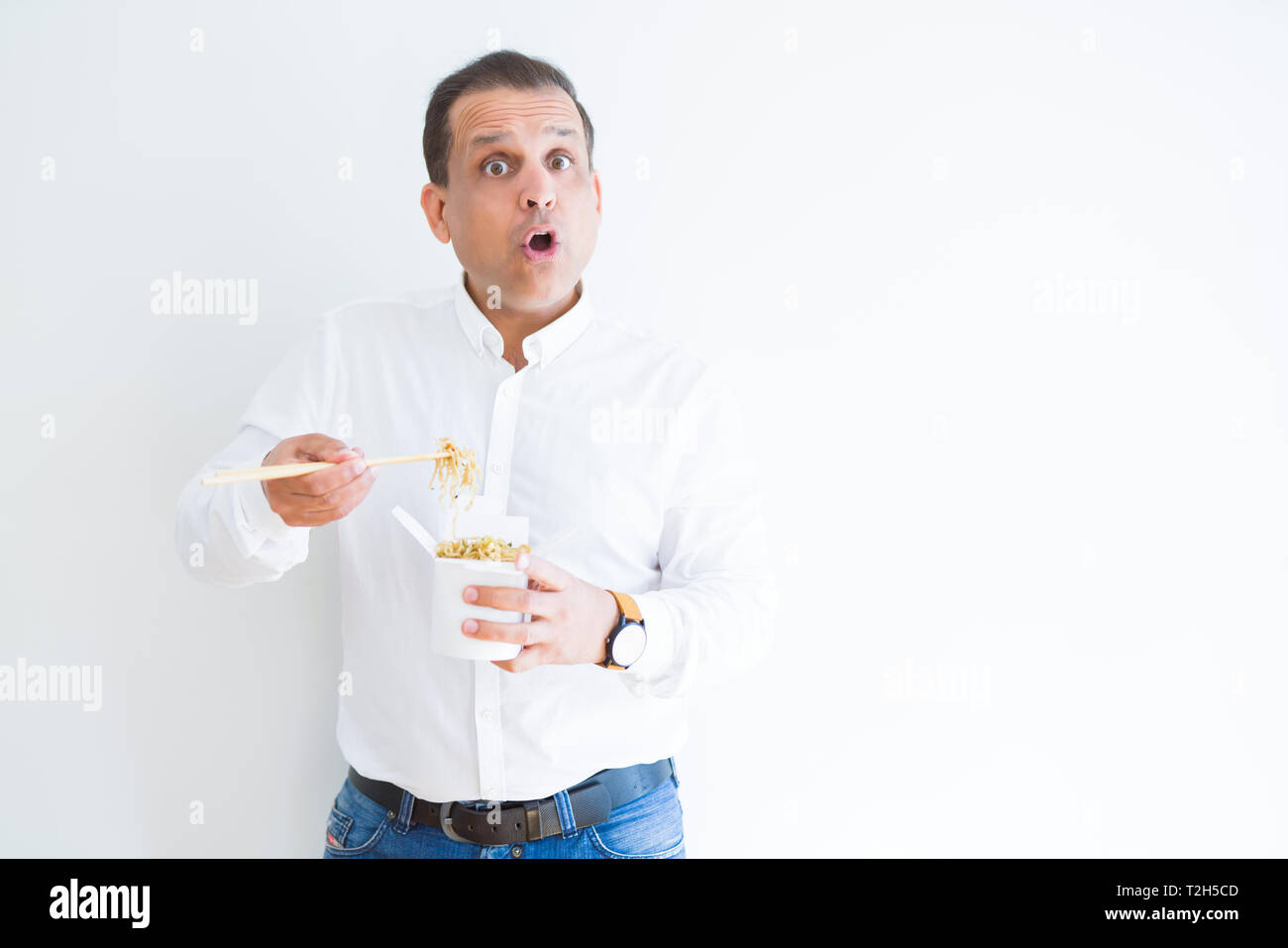 Middle age man eating asian noodles from take away carton scared in ...