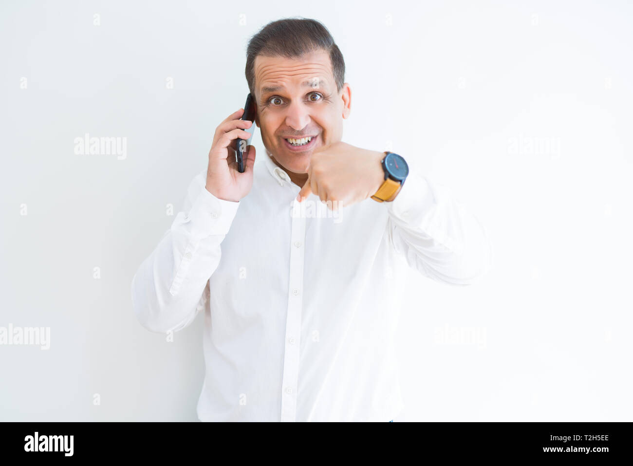Middle age man calling using smartphone with surprise face pointing ...