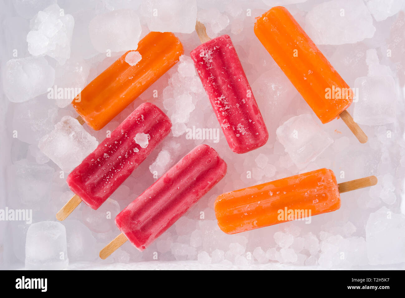 Orange and strawberry popsicles on ice cubes. Top view Stock Photo - Alamy
