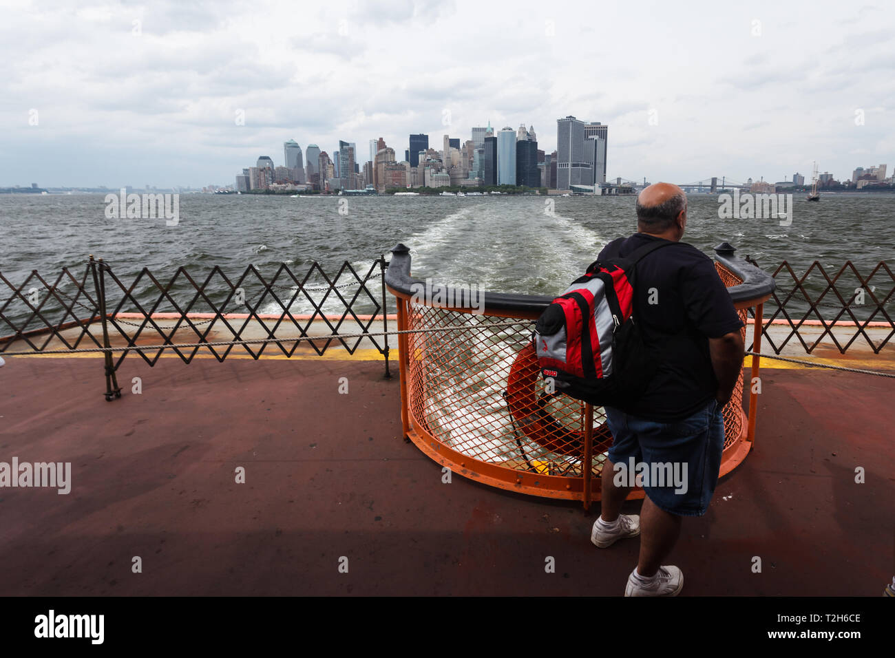 Tourist stands on back of ferry in New York City looking Lower ...