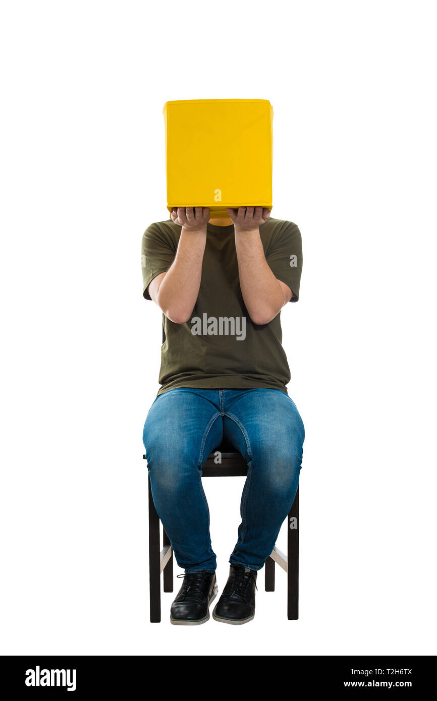 Full length portrait of casual incognito young man seated on a chair ...