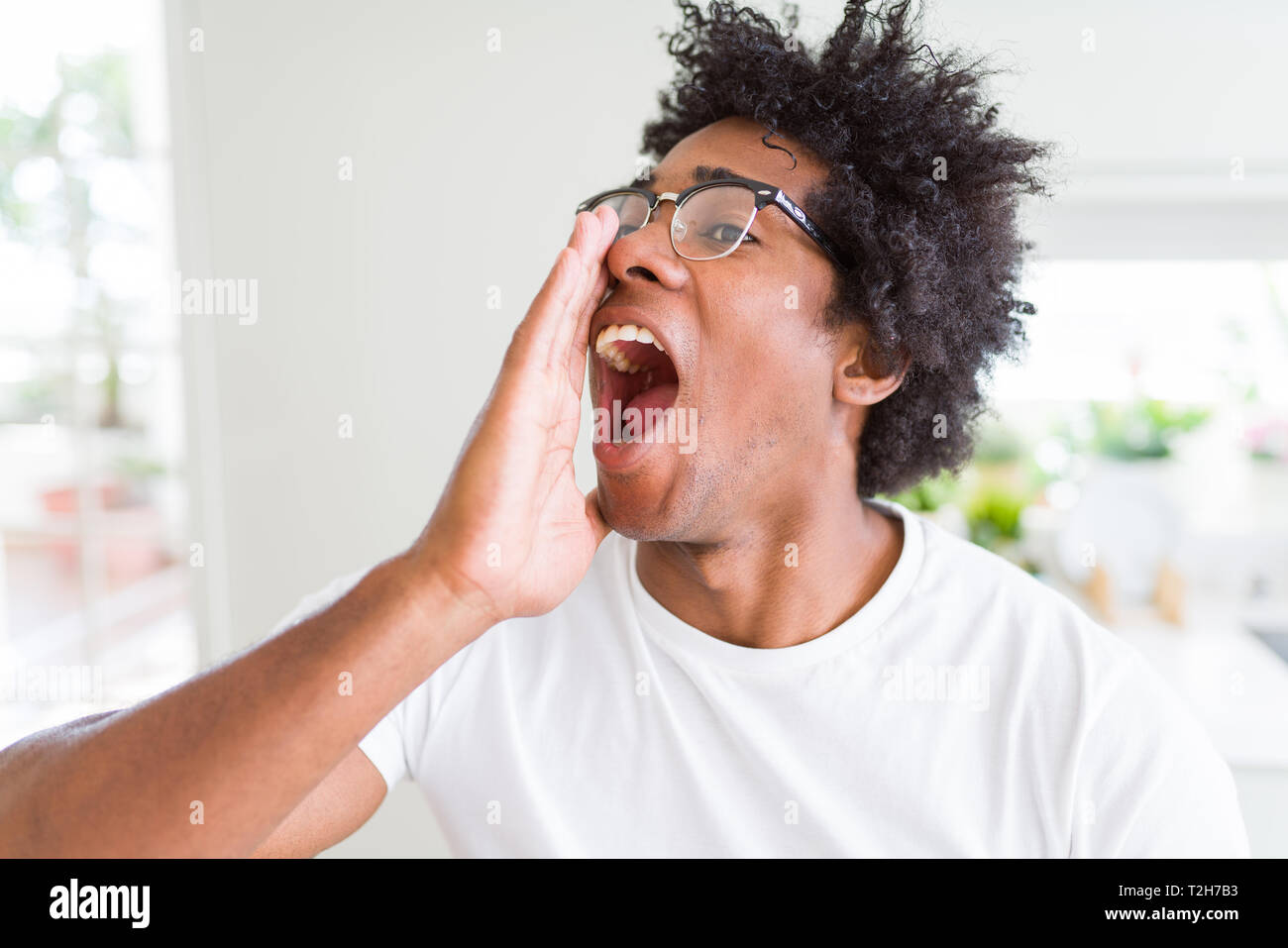 African American man wearing glasses shouting and screaming loud to ...