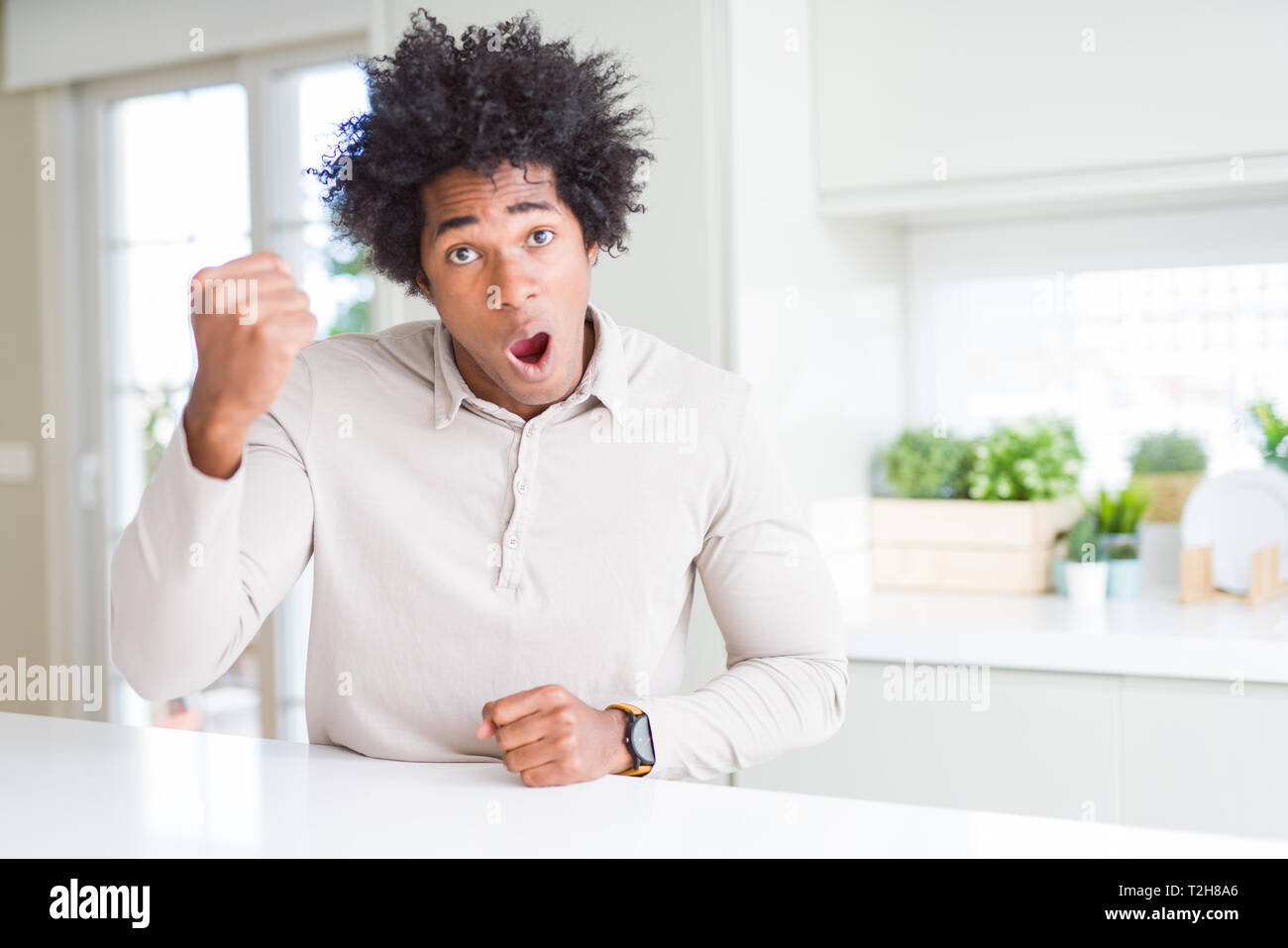 African American man at home angry and mad raising fist frustrated and ...