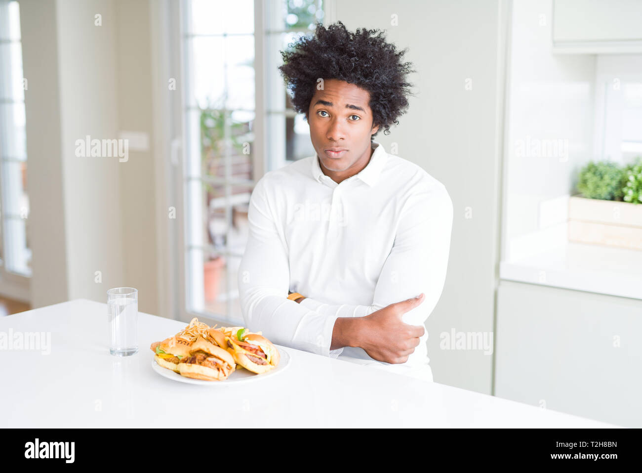 African American hungry man eating hamburger for lunch skeptic and ...