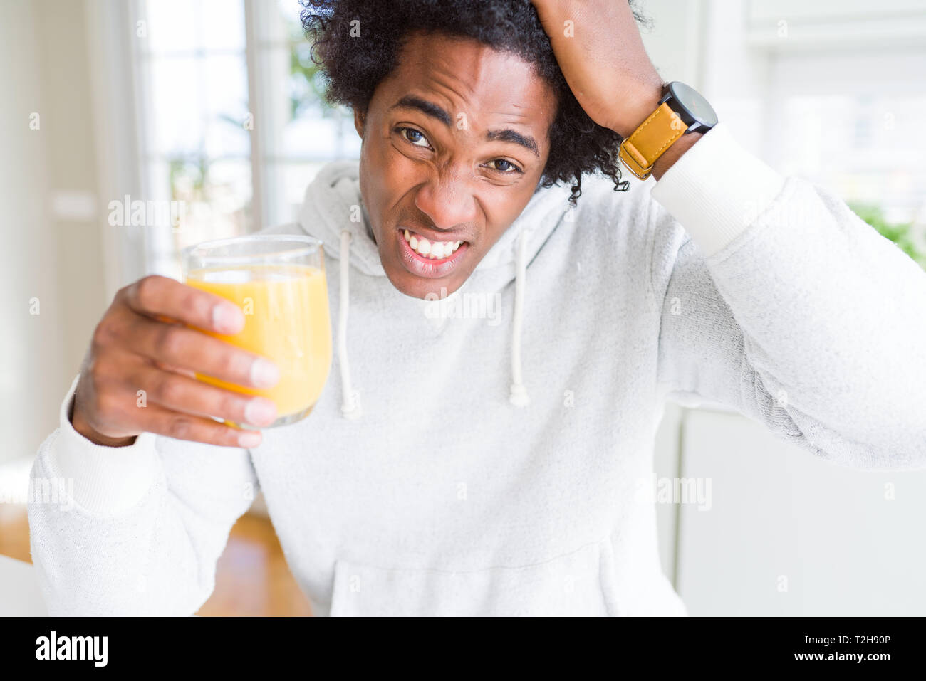African American man holding and drinking glass of orange juice ...