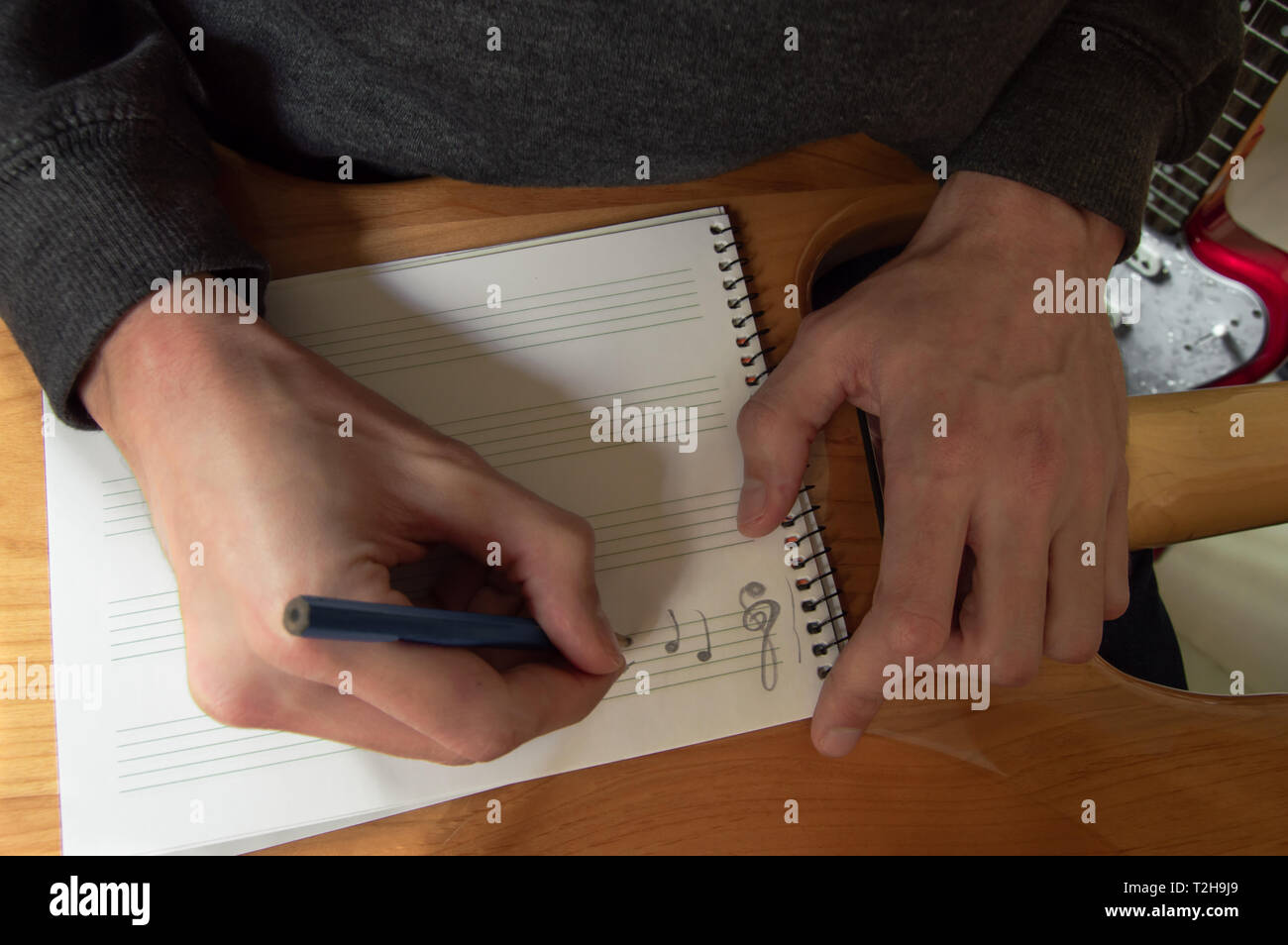 Young man composing music in a staff notebook placed on the back of a ...