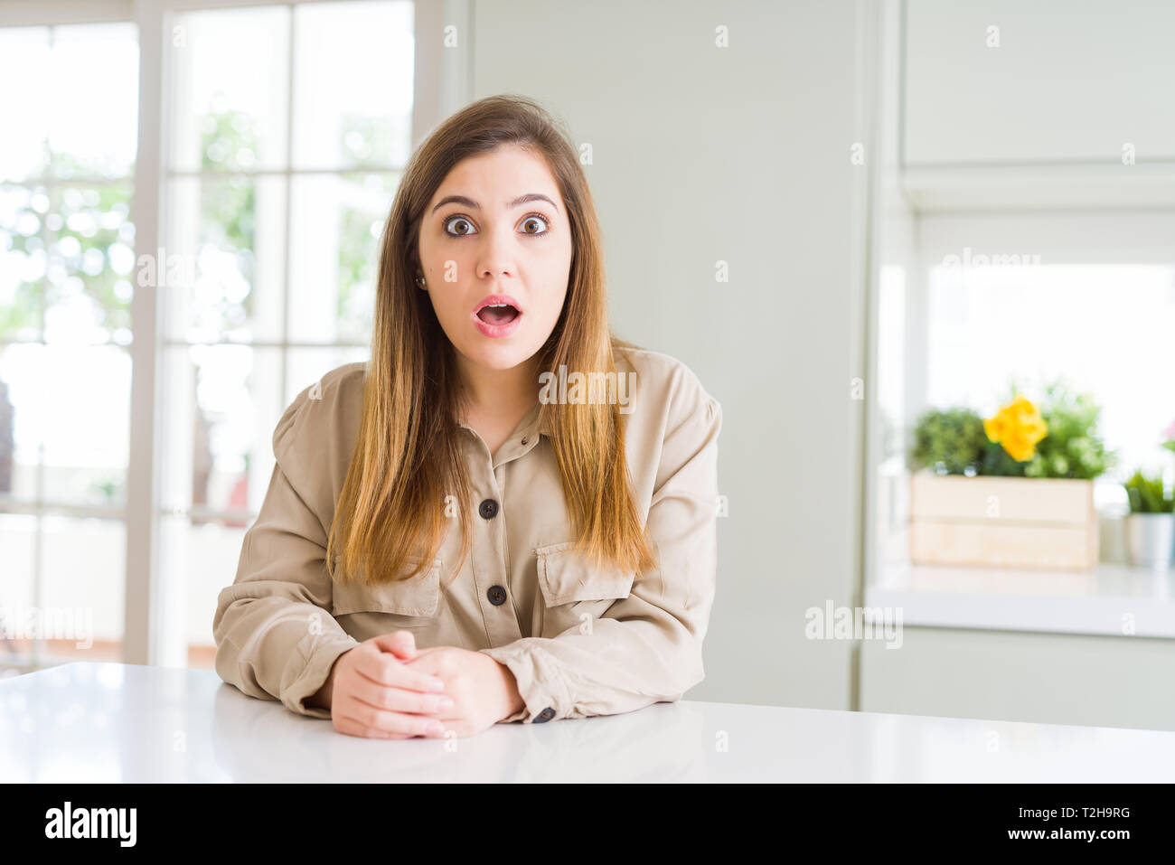 Beautiful young woman at home afraid and shocked with surprise ...