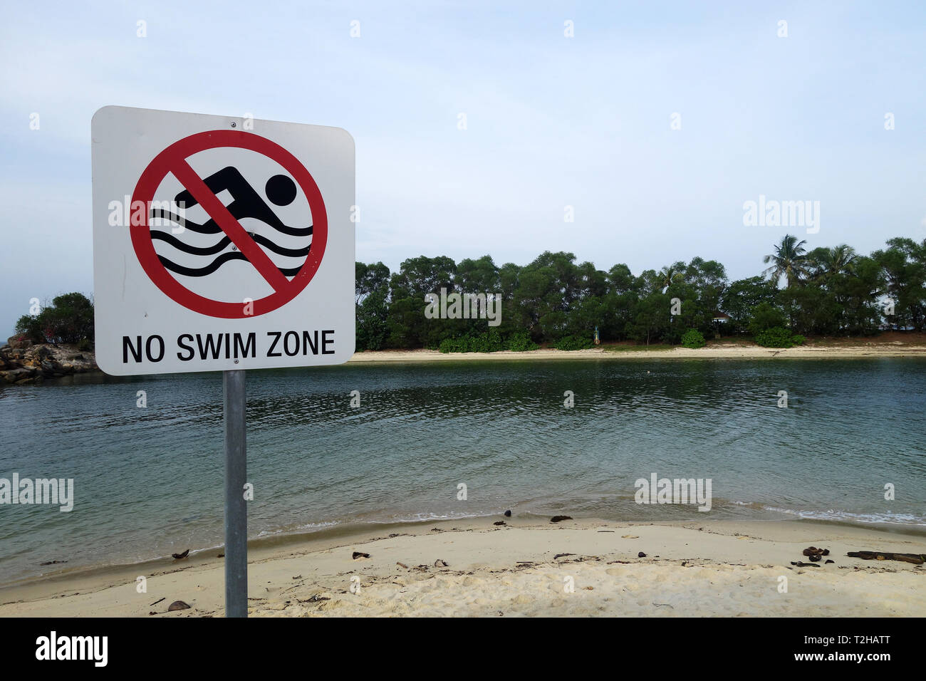 Tropical beach with sign warning to not swim Stock Photo - Alamy