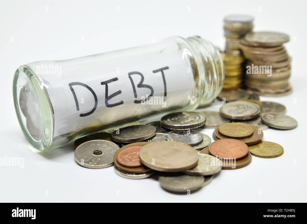 Debt lable in a glass jar with coins spilling out isolated on white ...
