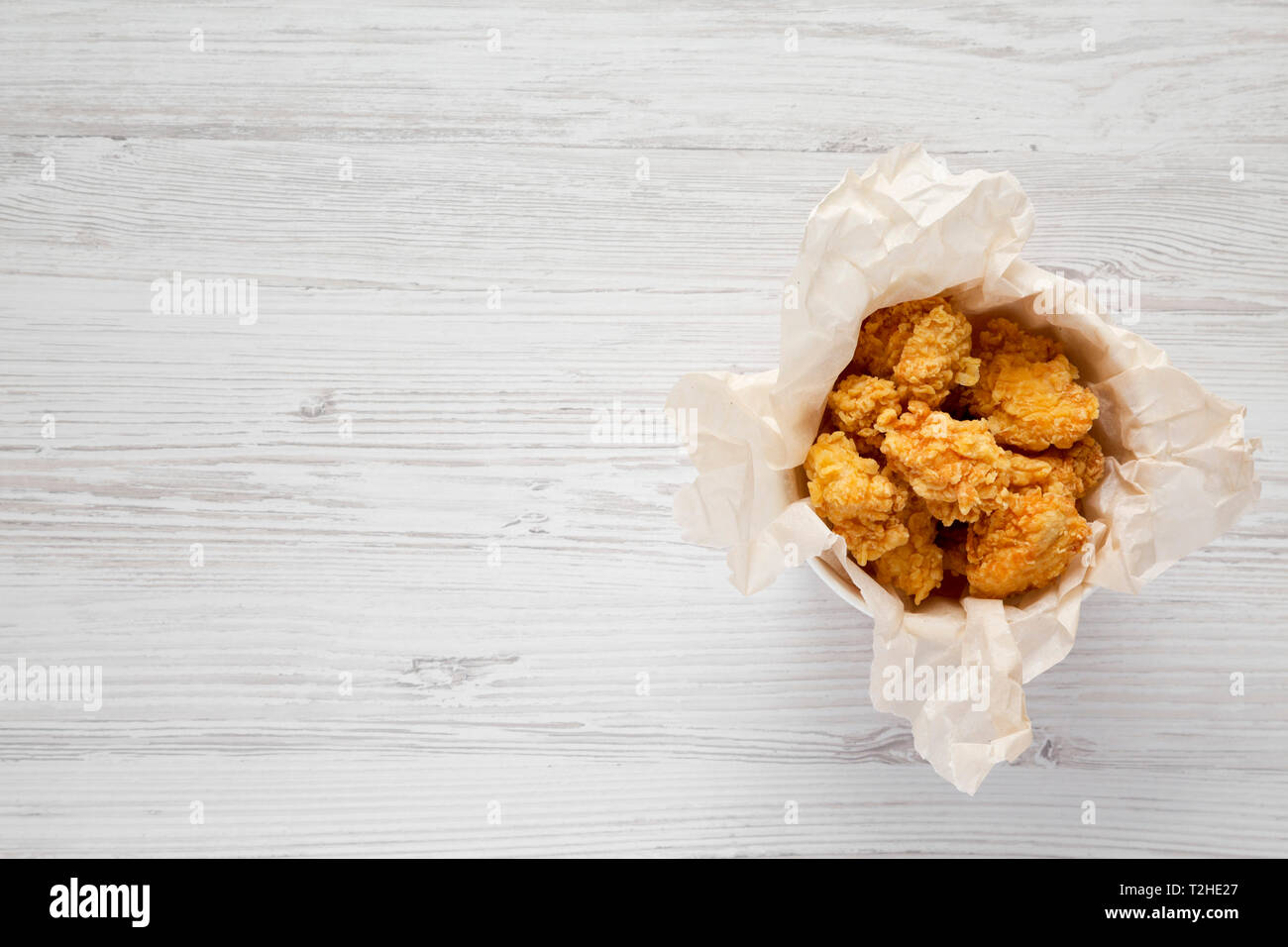 Chicken bites in paper box over white wooden background, top view. Flat ...