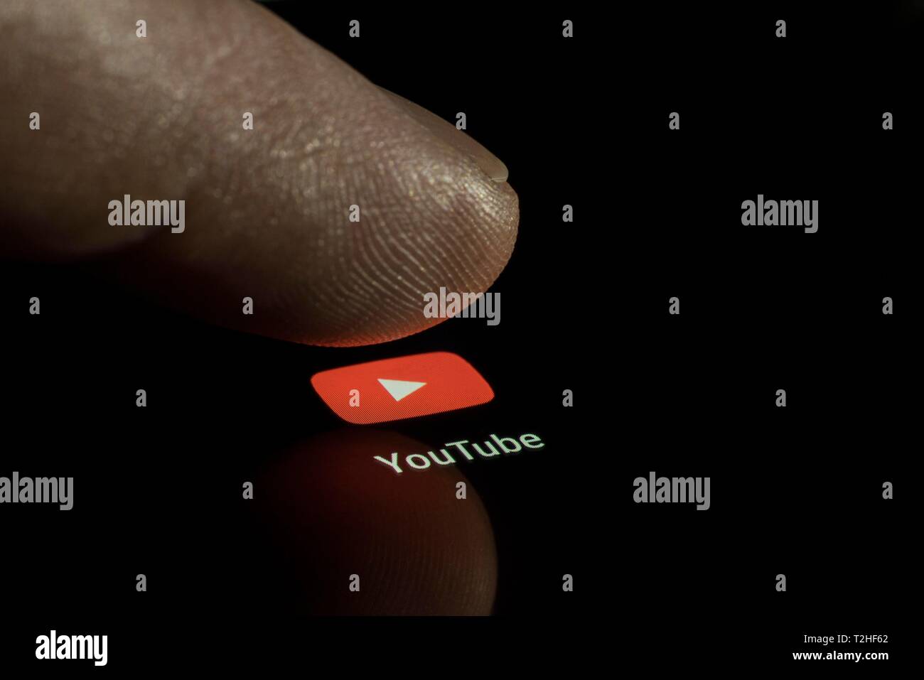 YouTube app icon on a display, with finger, mobile phone, smartphone ...