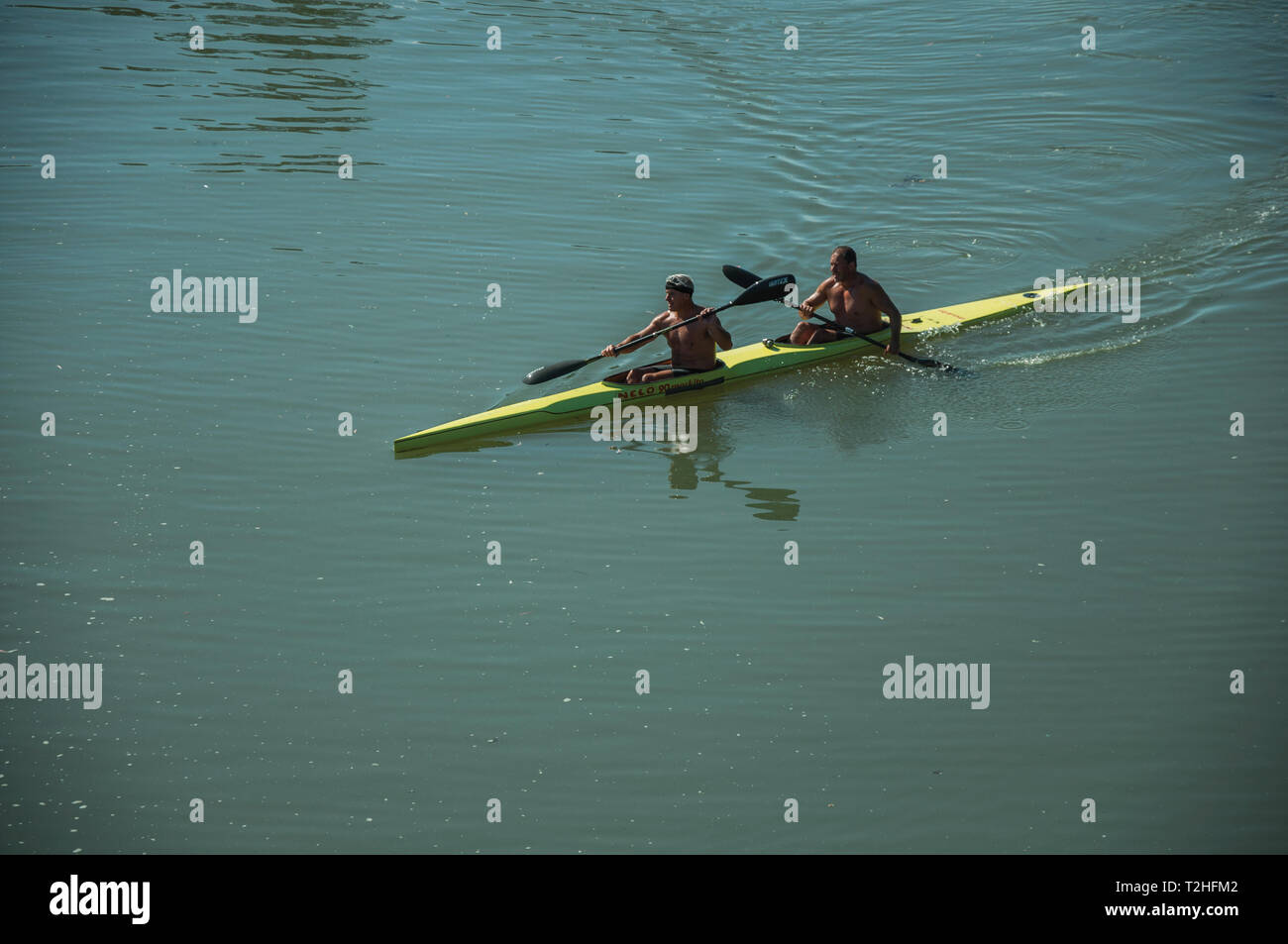 Two men on a kayak paddling on the surface of the Guadiana River in a ...