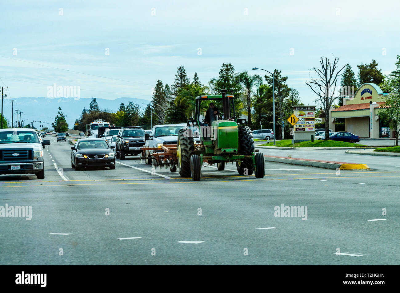 A John Deere tractor making a left turn at a suburban traffic light in ...
