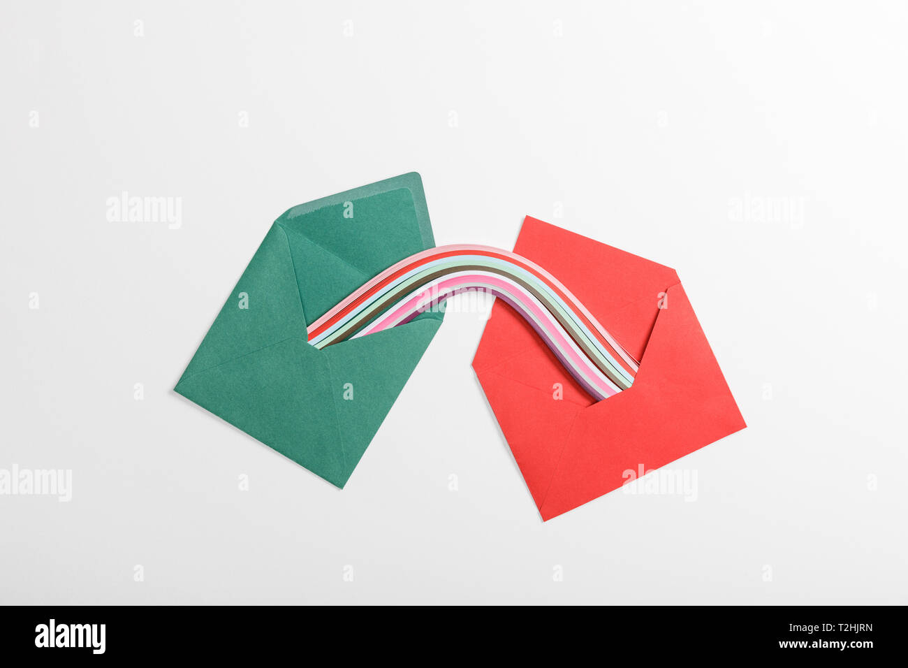 top view of green and red envelopes with multicolored rainbow on grey ...