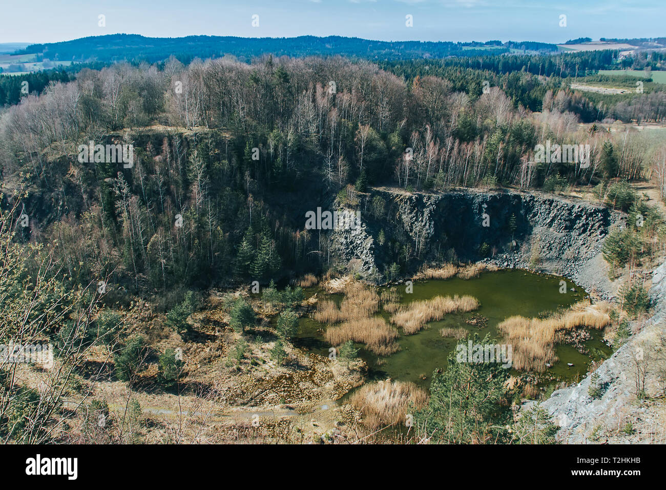 Aerial view to swamped quarry with high dry grass, small pond, rock ...