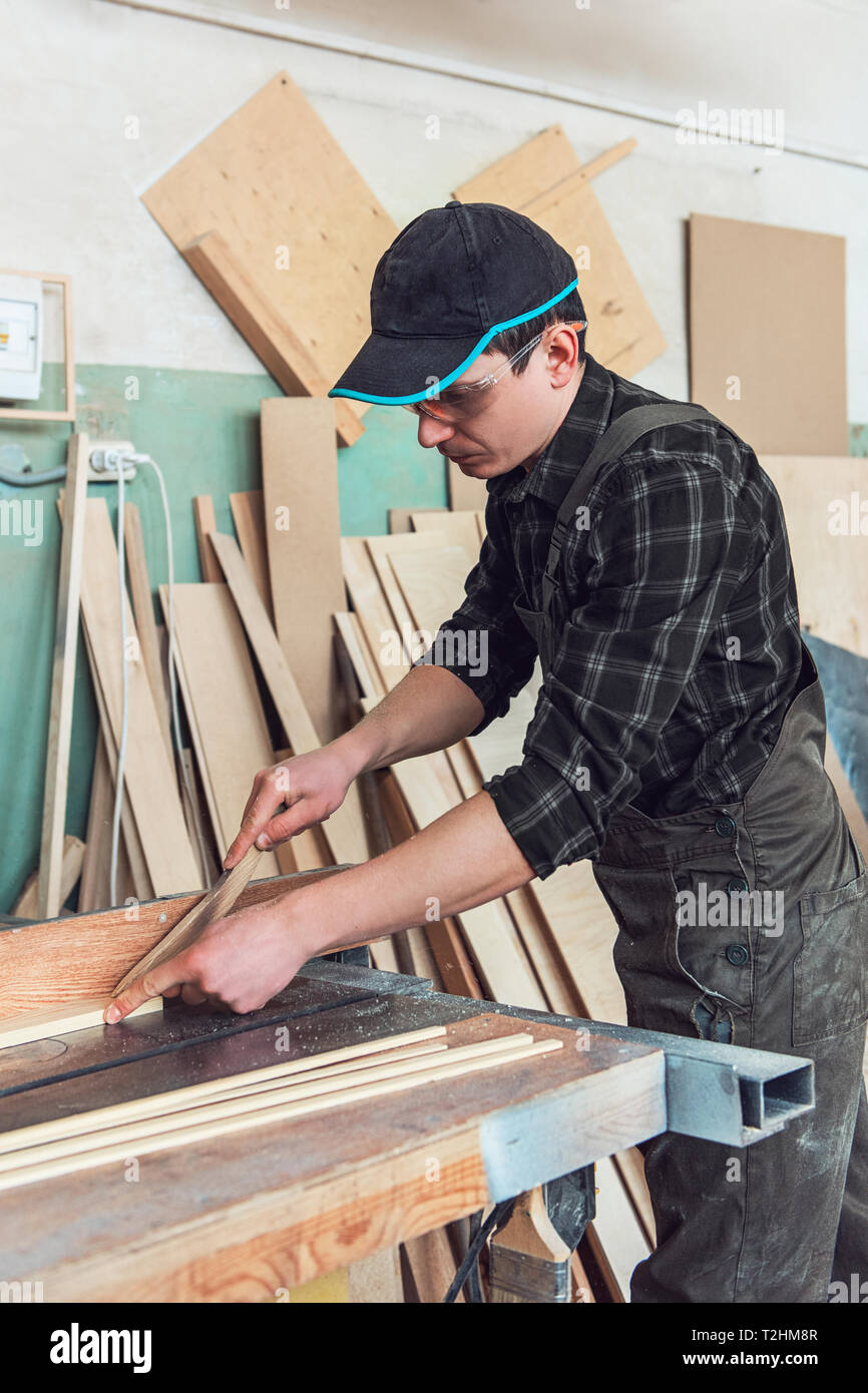 Carpenter worker cutting wooden board with circular saw. Profession ...