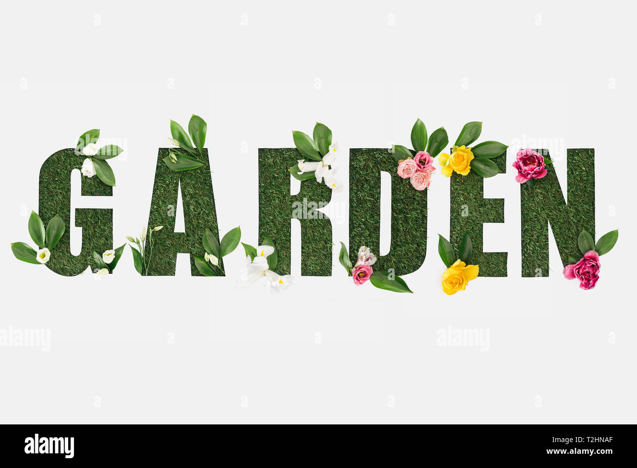 top view of cut out garden lettering on green grass with flowers ...