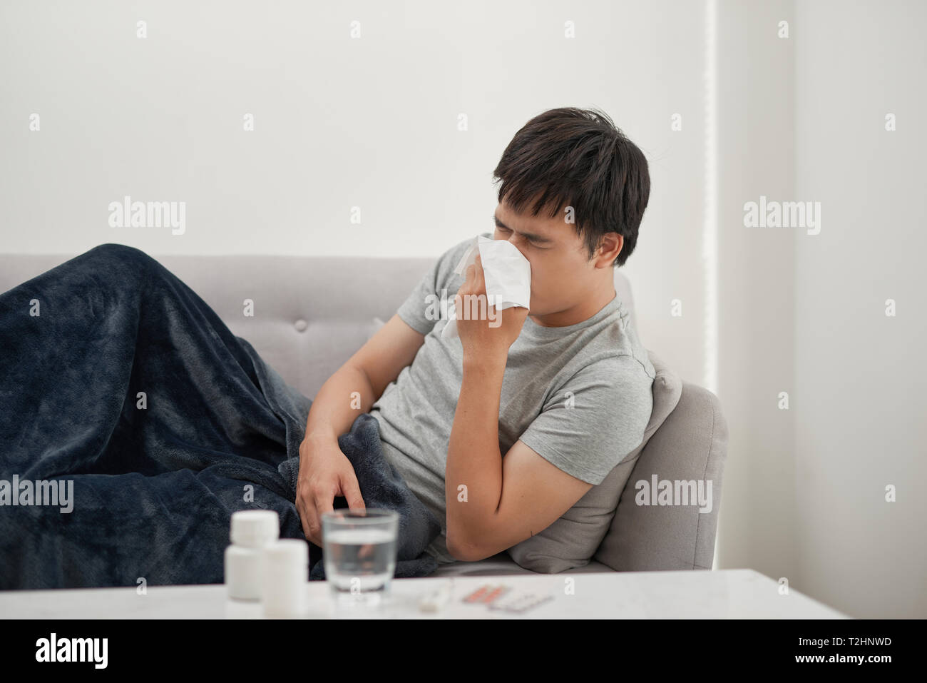 Man feeling cold, lying in the bed and blowing his nose Stock Photo - Alamy
