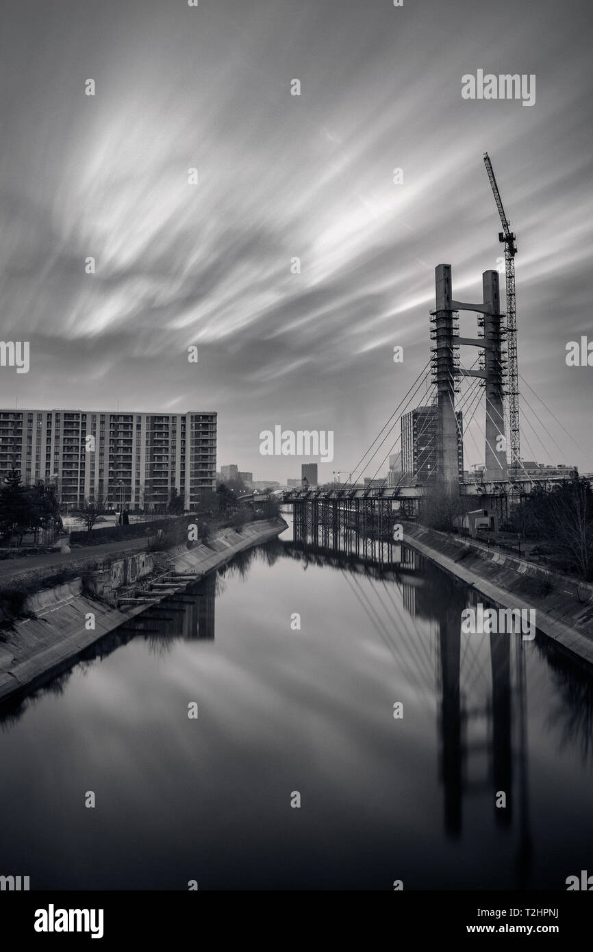 Black and white long exposure cityscape with a bridge in construction ...
