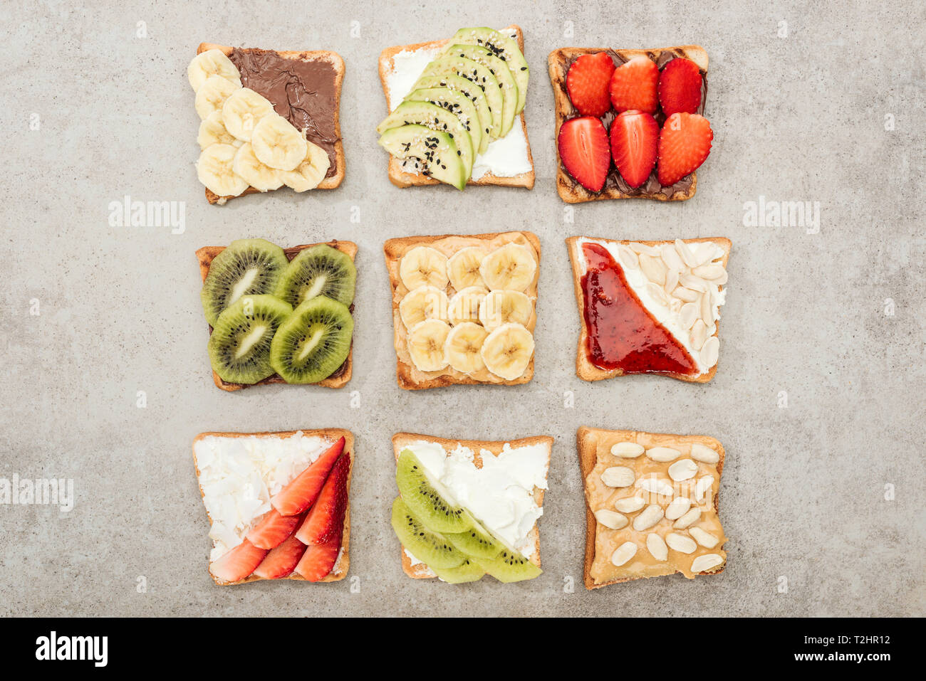 Top view of toasts with cut fruits, berries and peanuts on textured ...