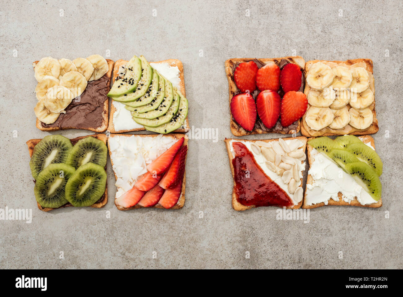 Top view of toasts with cut fruits, berries and peanuts on textured ...