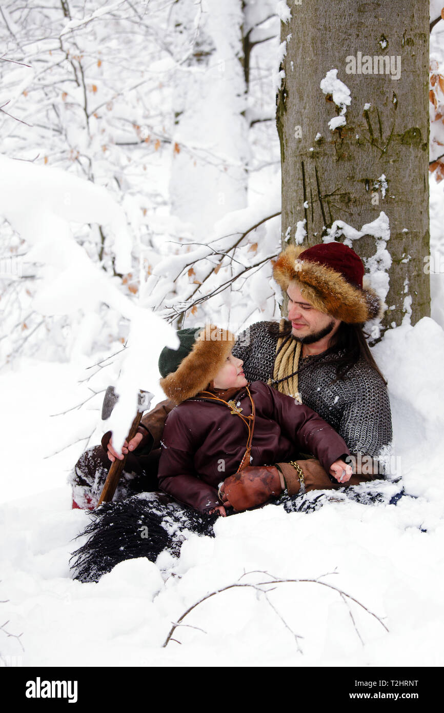 Father and son Vikings in a deep winter forest and the father teaches ...