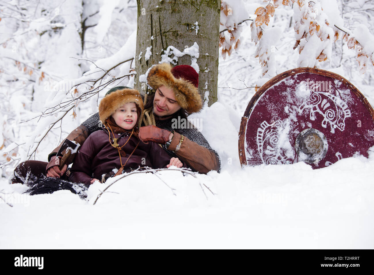 Father and son Vikings in a deep winter forest and the father teaches ...
