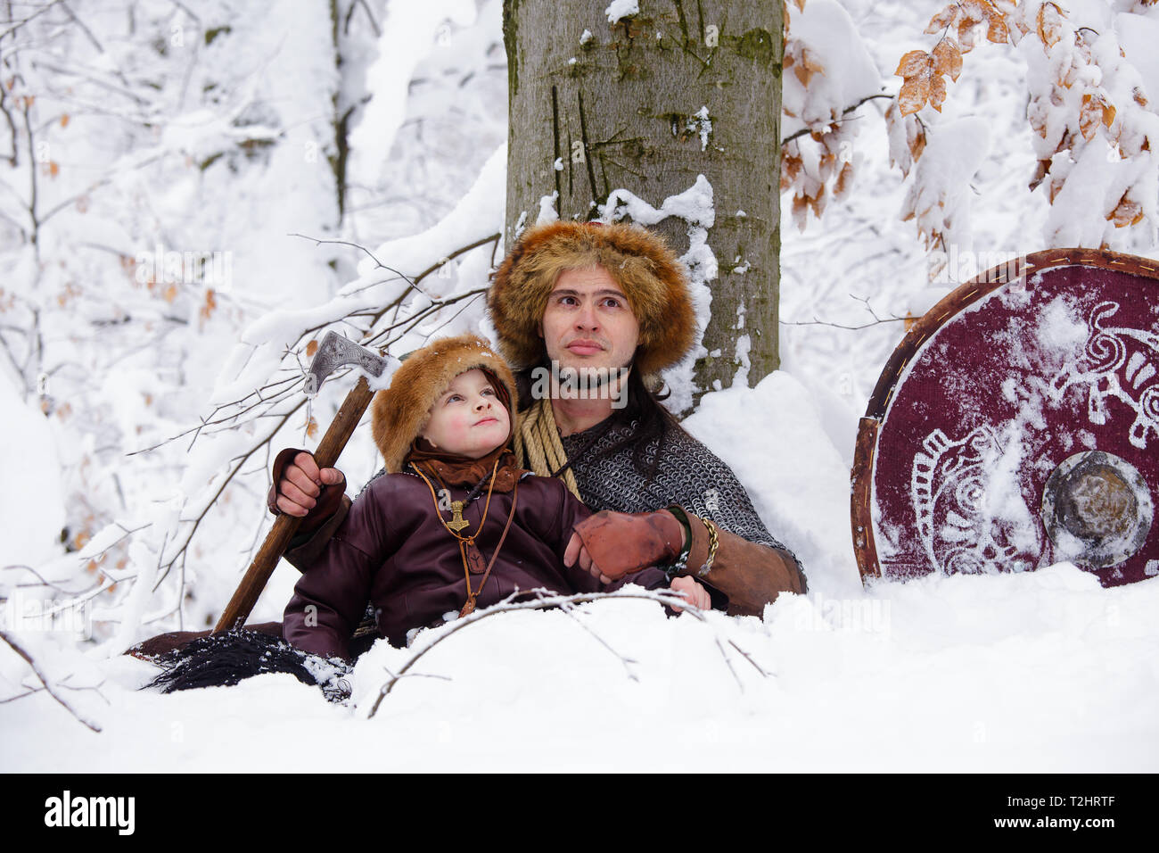Father and son Vikings in a deep winter forest and the father teaches ...