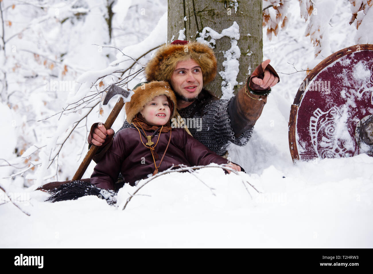 Father and son Vikings in a deep winter forest and the father teaches ...