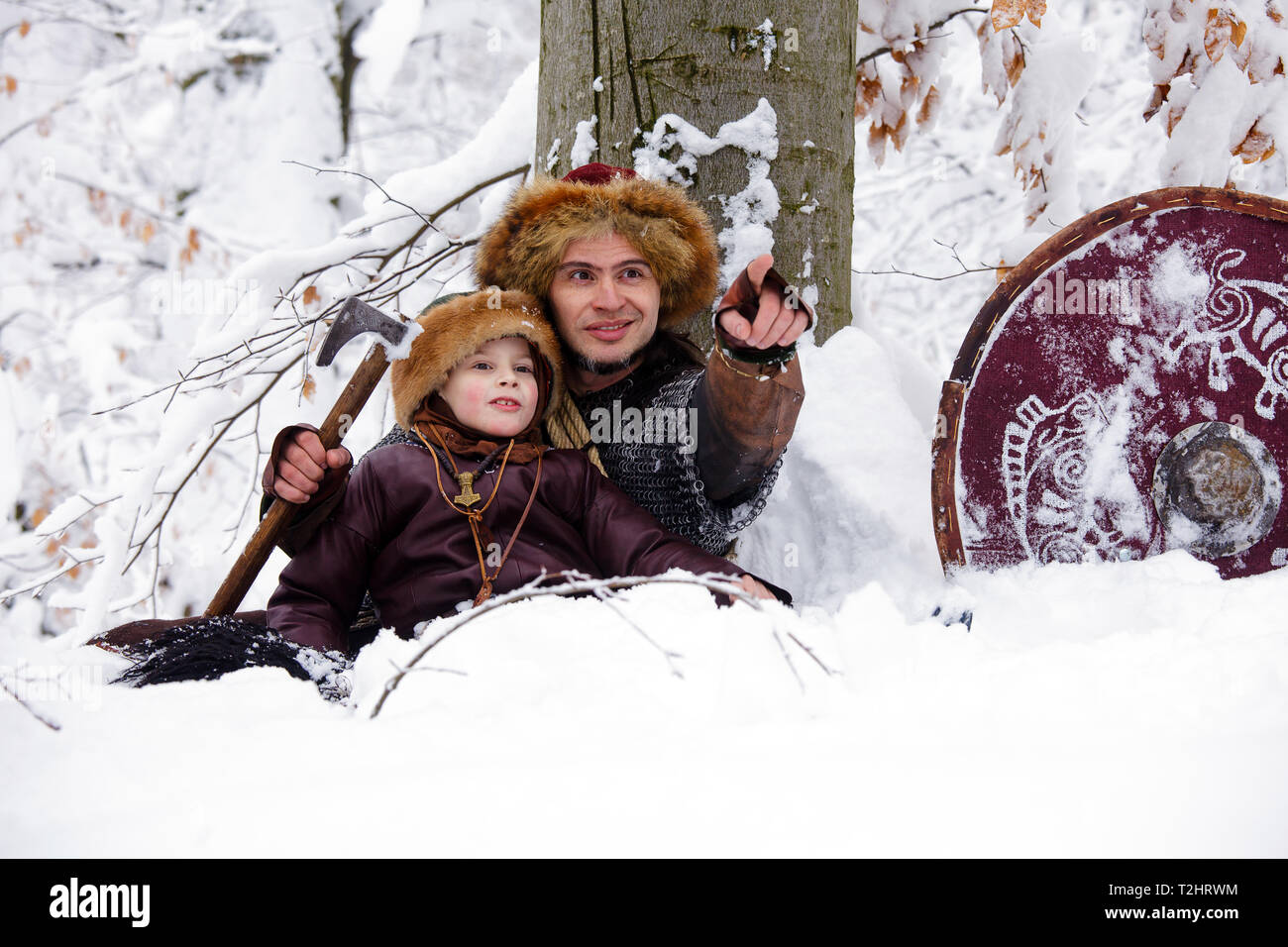 Father and son Vikings in a deep winter forest and the father teaches ...