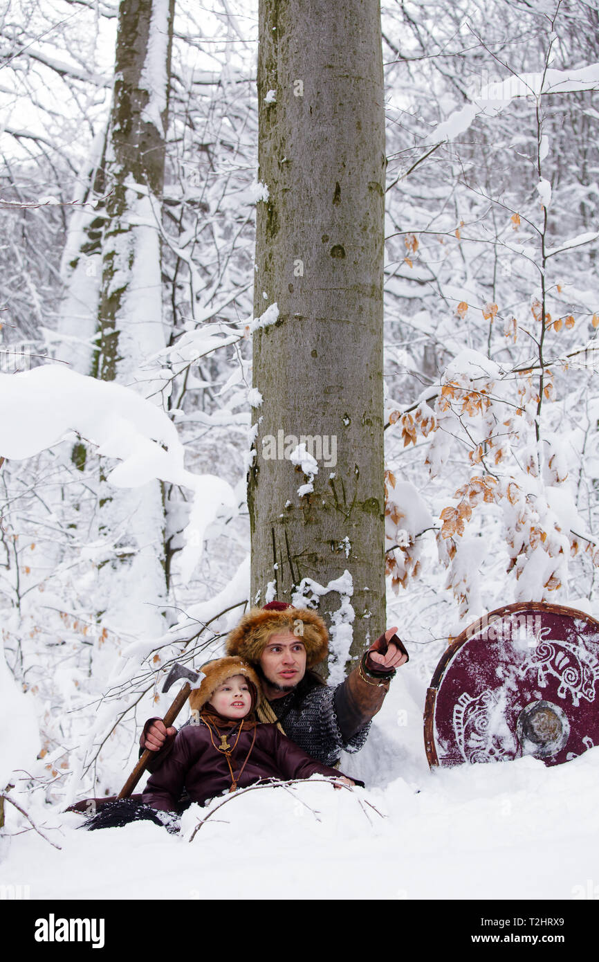 Father and son Vikings in a deep winter forest and the father teaches ...