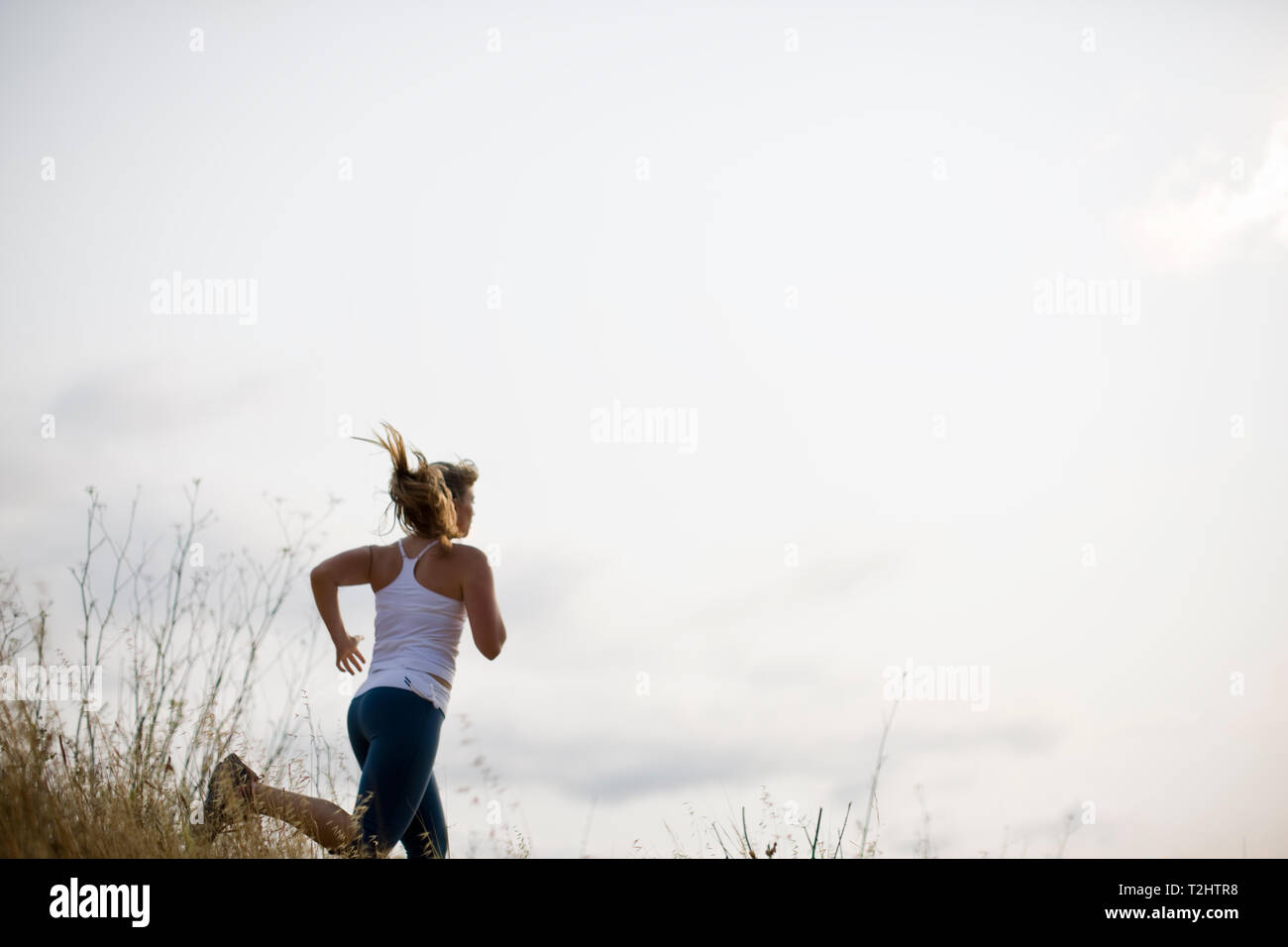 Teenage girl running along a track in a field Stock Photo - Alamy