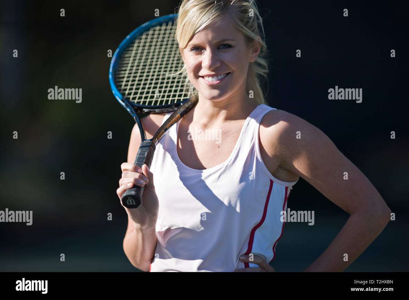 Portrait of young woman holding tennis racquet Stock Photo - Alamy