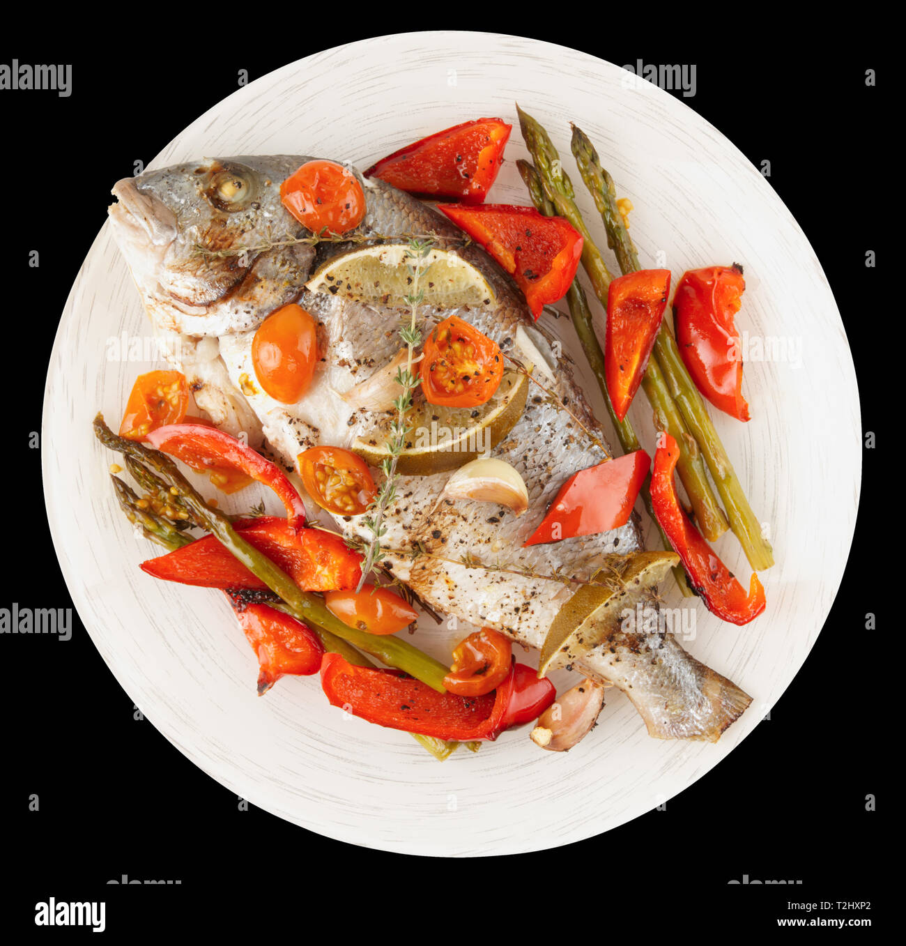 Roasted gilt-head bream with vegetables on plate, isolated on white ...