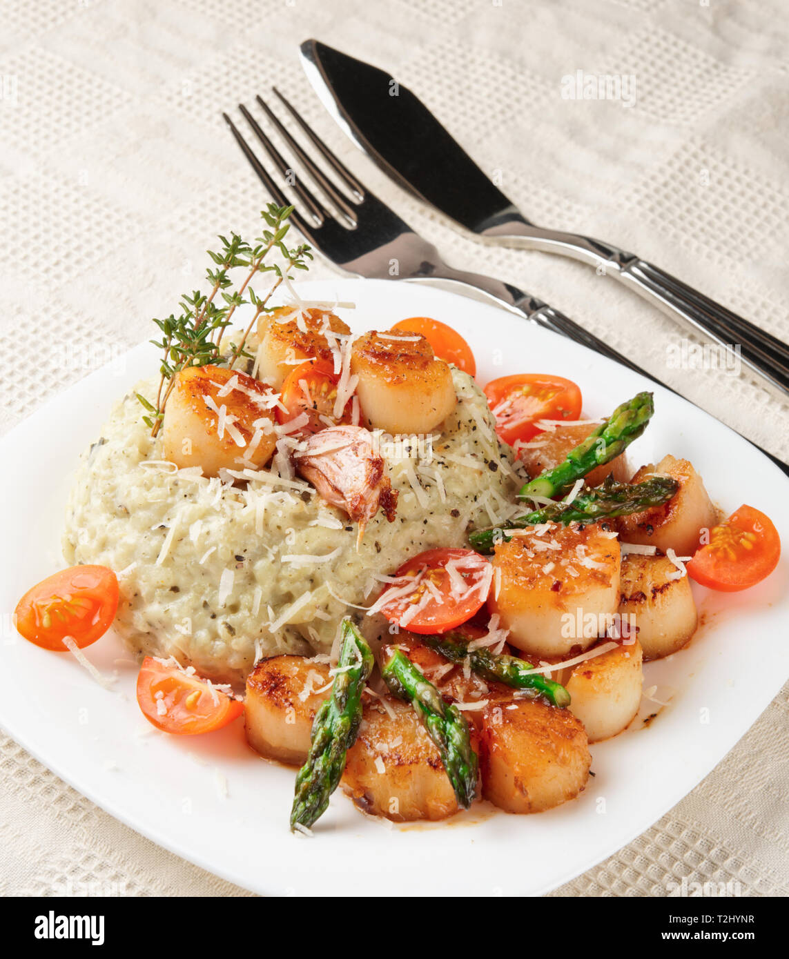 Risotto with pan seared sea scallops on served table Stock Photo - Alamy