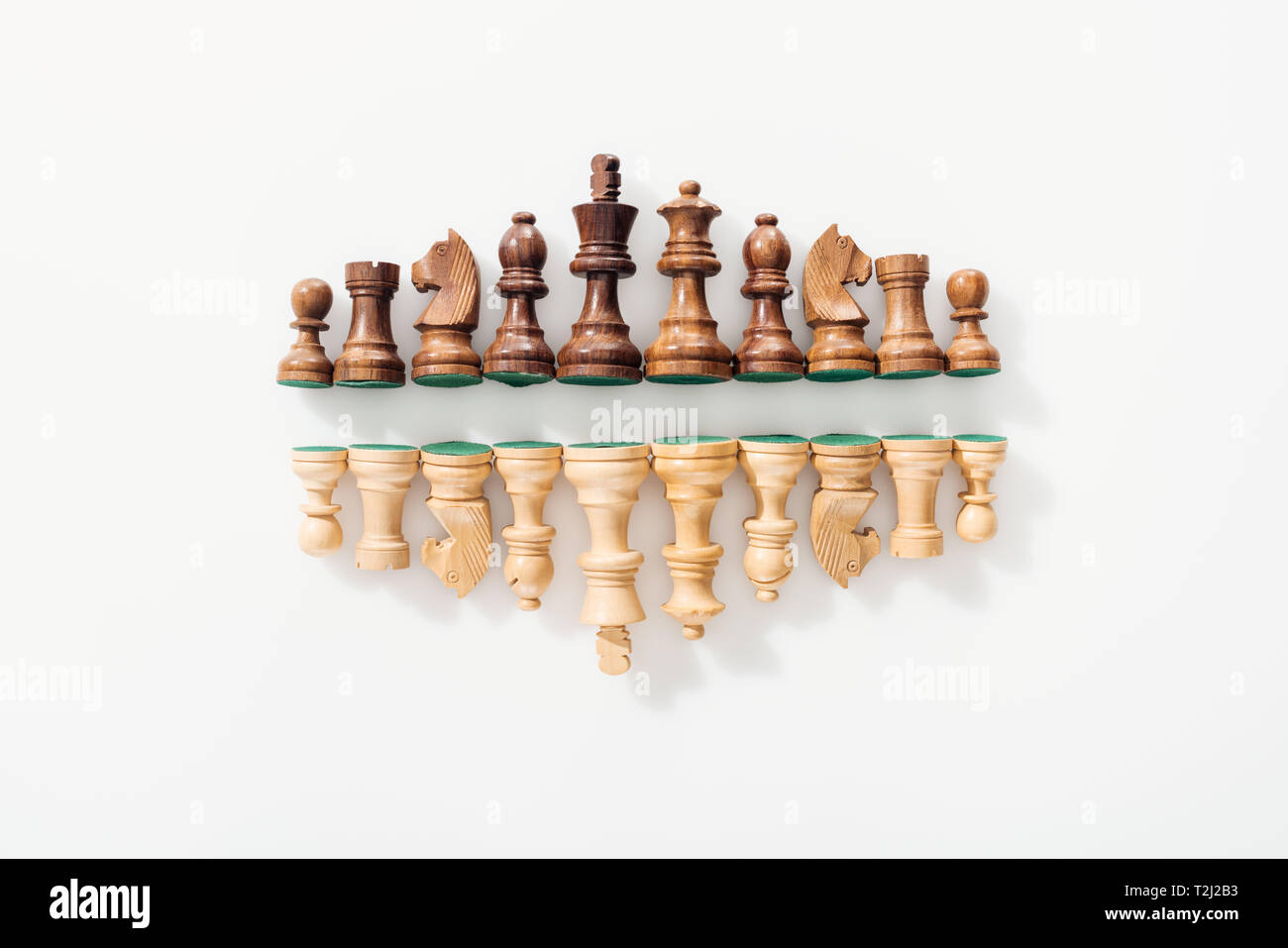 top view of rows made of brown and beige wooden chess figures on white ...
