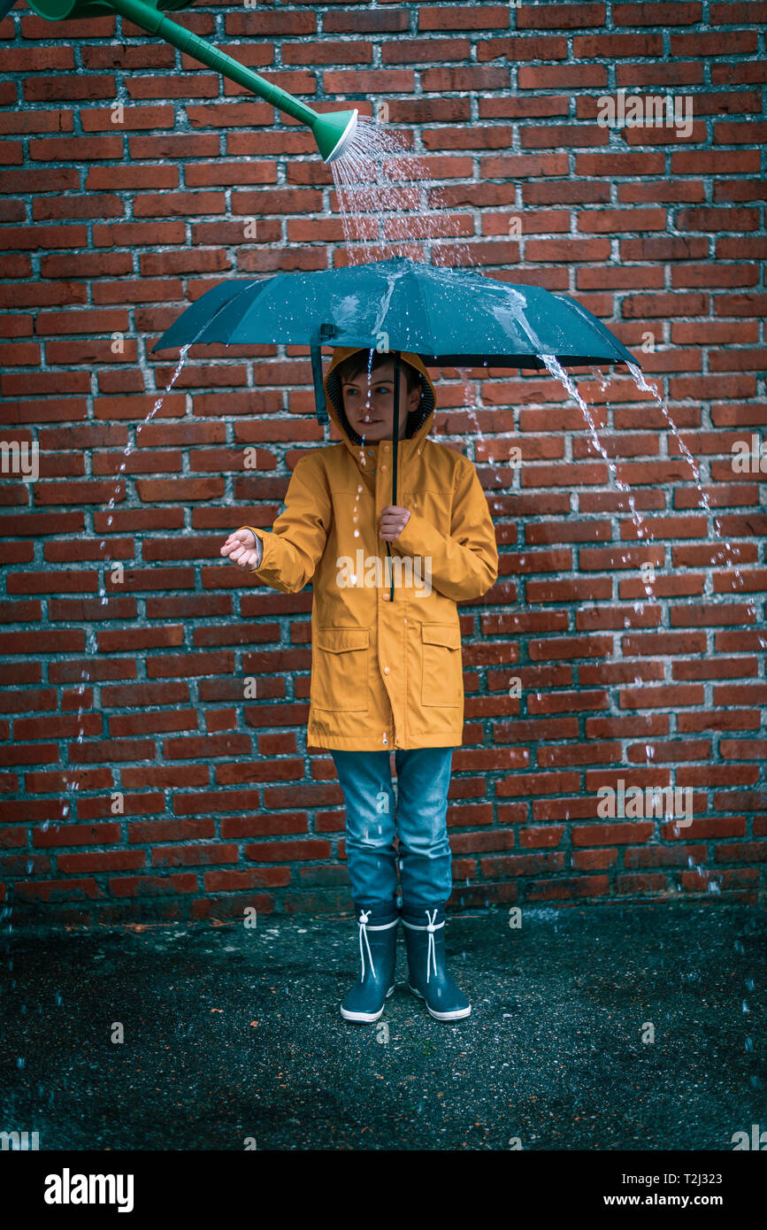 boy with umbrella standing under a watering can forsome fake rain Stock ...