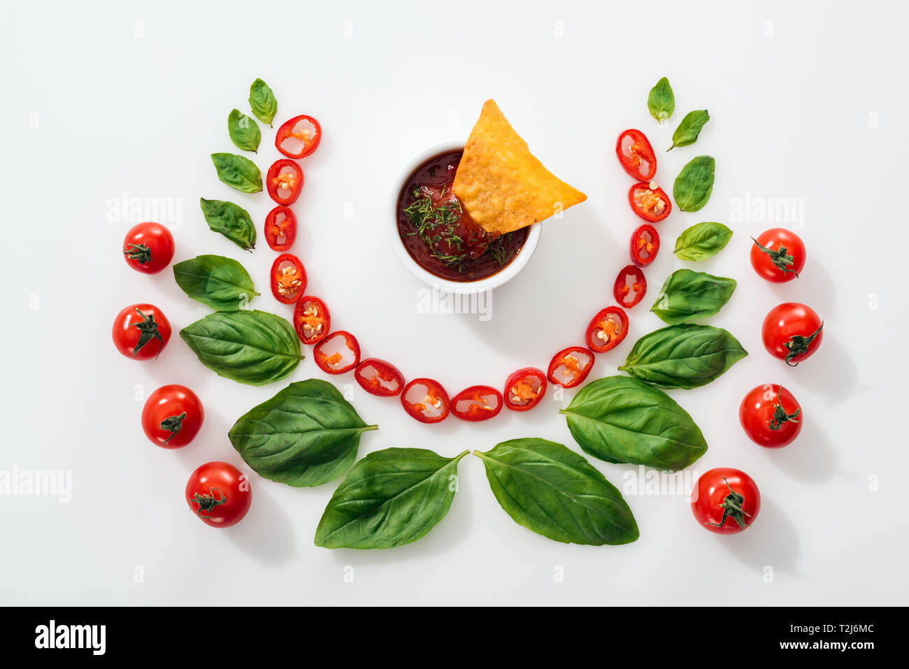 flat lay with cut chili peppers, basil leaves, nachos in sauce and ripe ...
