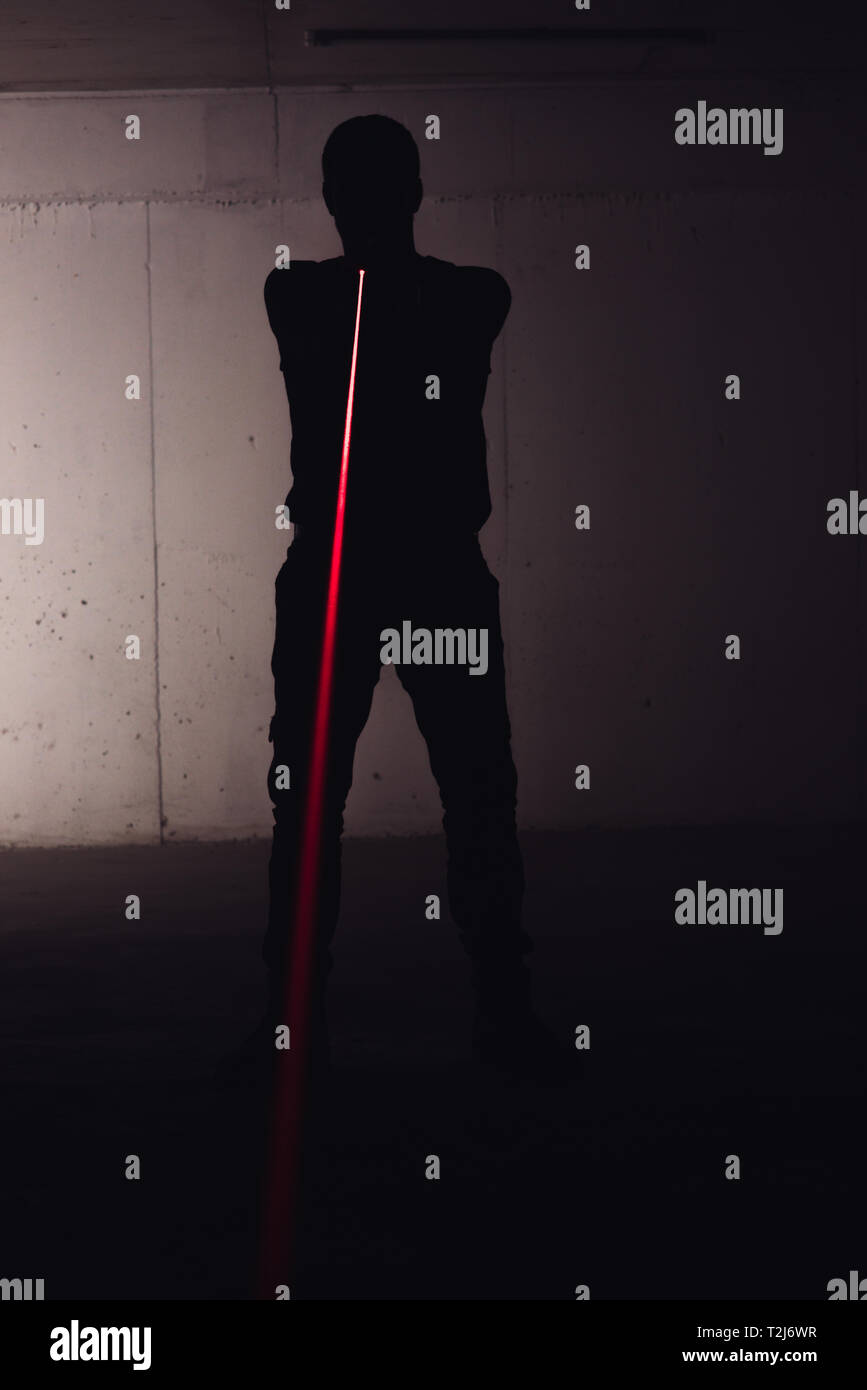 silhouette of an armed man holding his gun and pointing with his laser ...