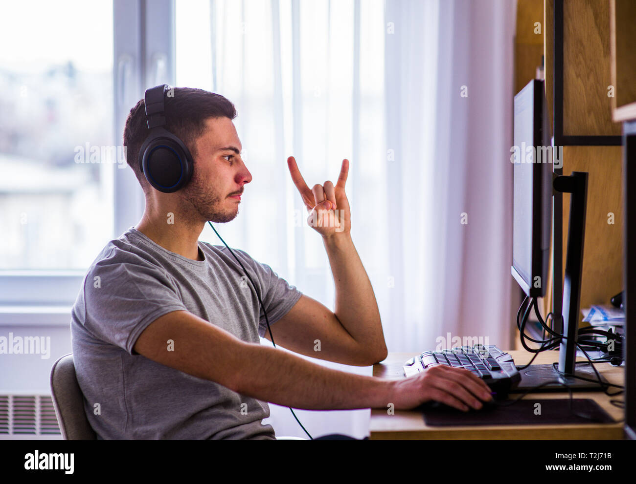 Concentrated bristled young man sitting and looking at screen of ...